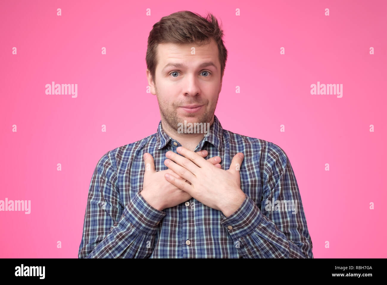 Cheerful young man smiles happily, keeps hands on chest, expresses his ...