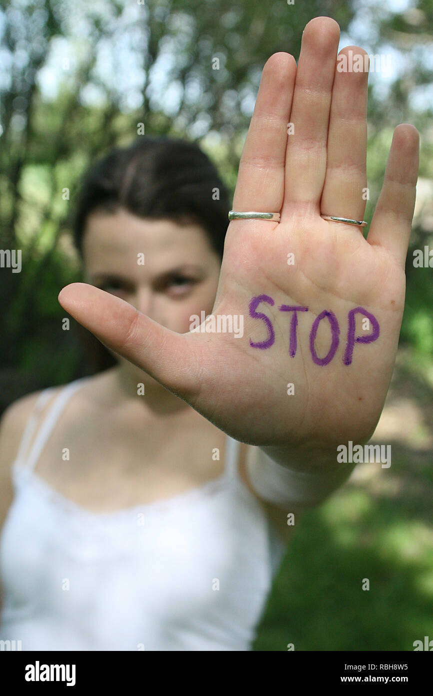 Brunette girl in a park outdoors on a sunny day giving hand signals ...