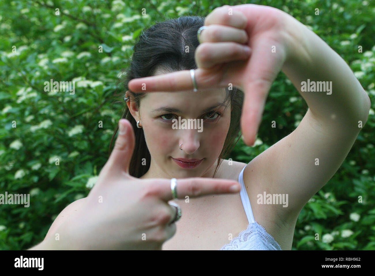 Brunette girl in a park outdoors on a sunny day giving hand signals ...