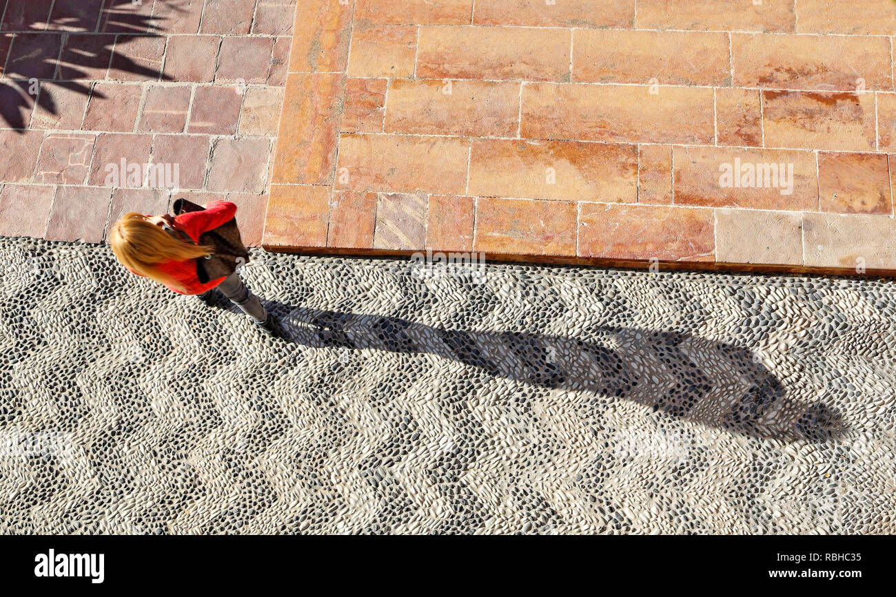 A woman walking with a great shadow on the floor Stock Photo - Alamy