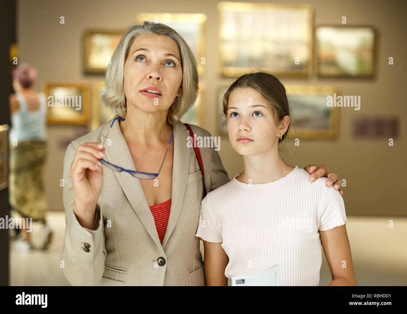 Attentive tween girl with senior woman looking with interest at gallery ...