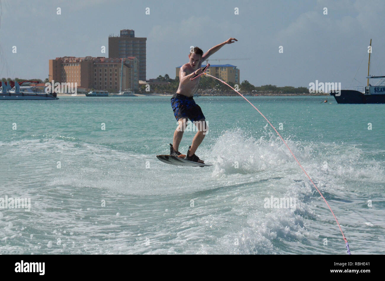 Young guy wakeboarding and jumping over the boats wake Stock Photo - Alamy