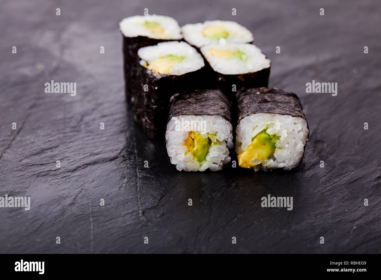 Avocado sushi roll on black slate board Stock Photo - Alamy