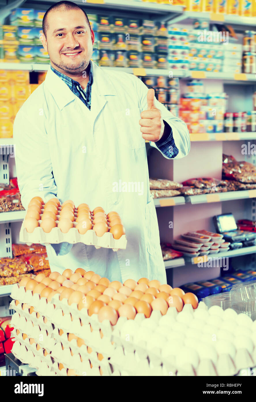 Adult salesman offering chicken eggs in ordinary food shop Stock Photo ...
