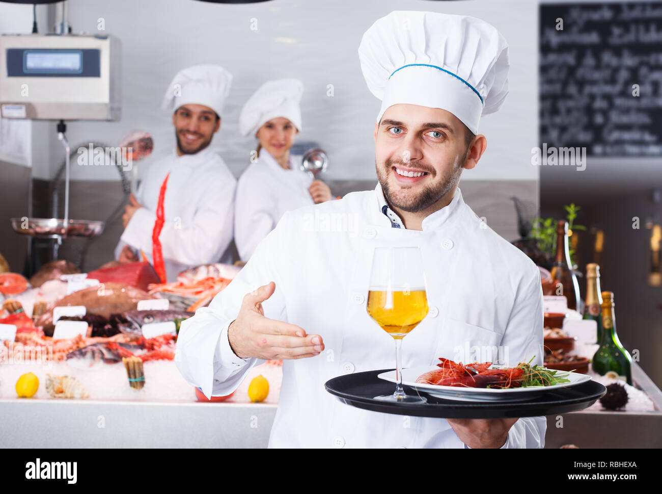 Handsome smiling male chef with dishes on serving tray welcoming to ...