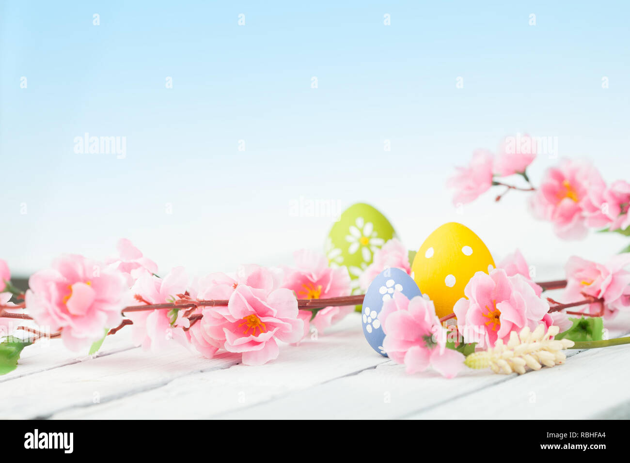 Colored eggs with pink flowers on white wooden background Stock Photo ...
