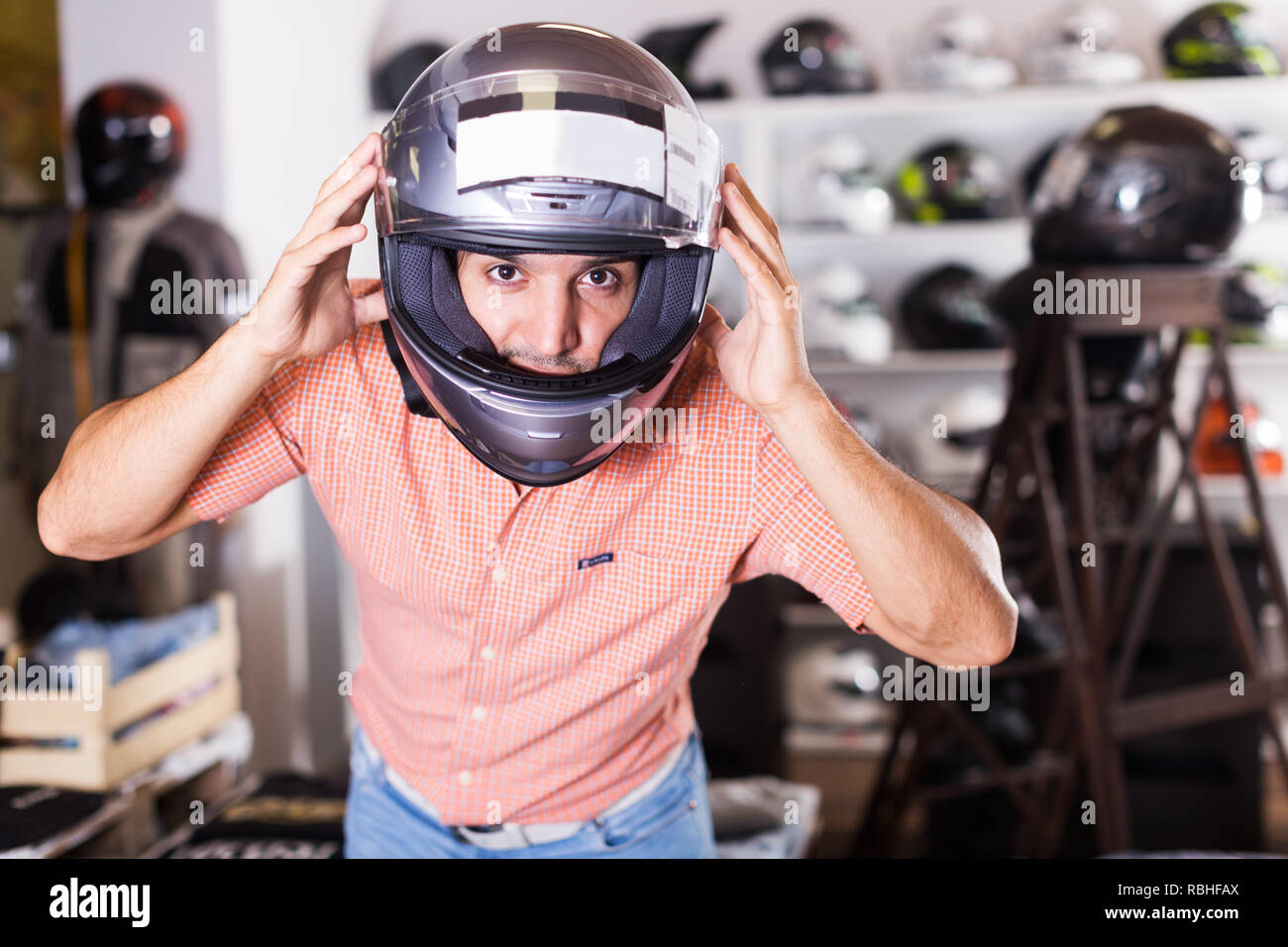 Happy male customer is trying up modern helmet in the sport store Stock ...