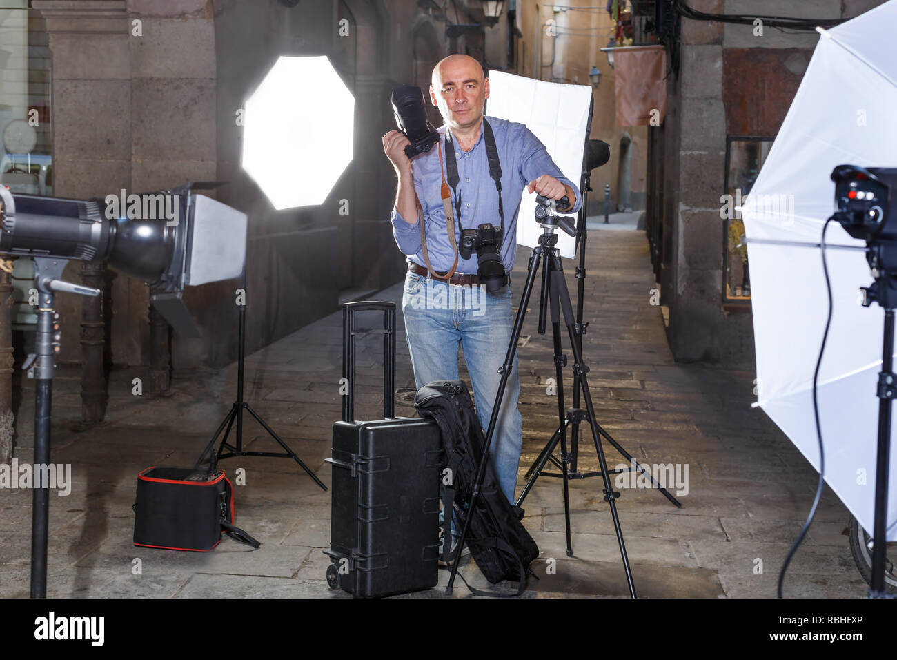 Portrait of male photographer standing with camera among professional ...