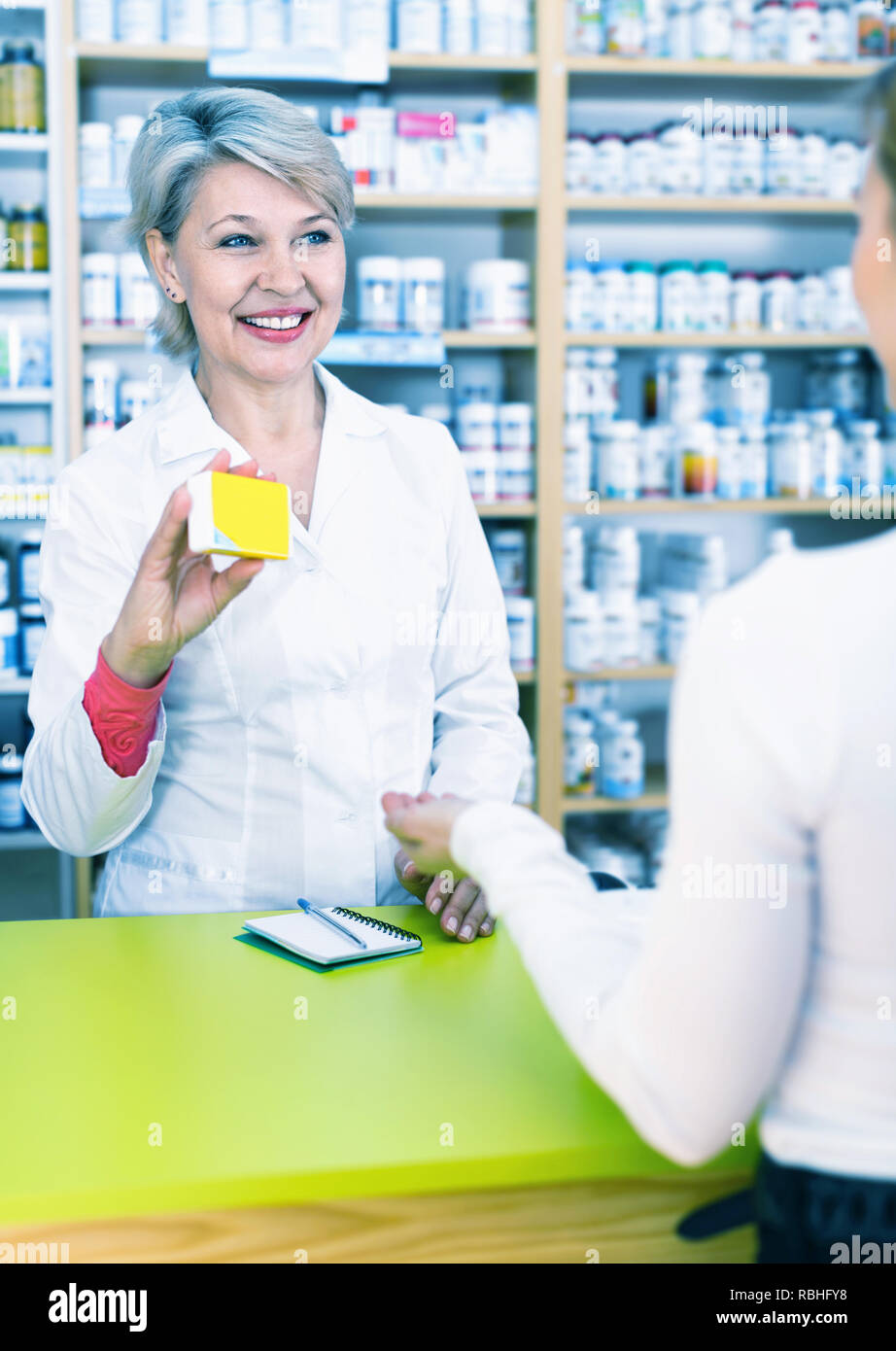 Cheerful positive smiling mature female seller suggesting care products ...