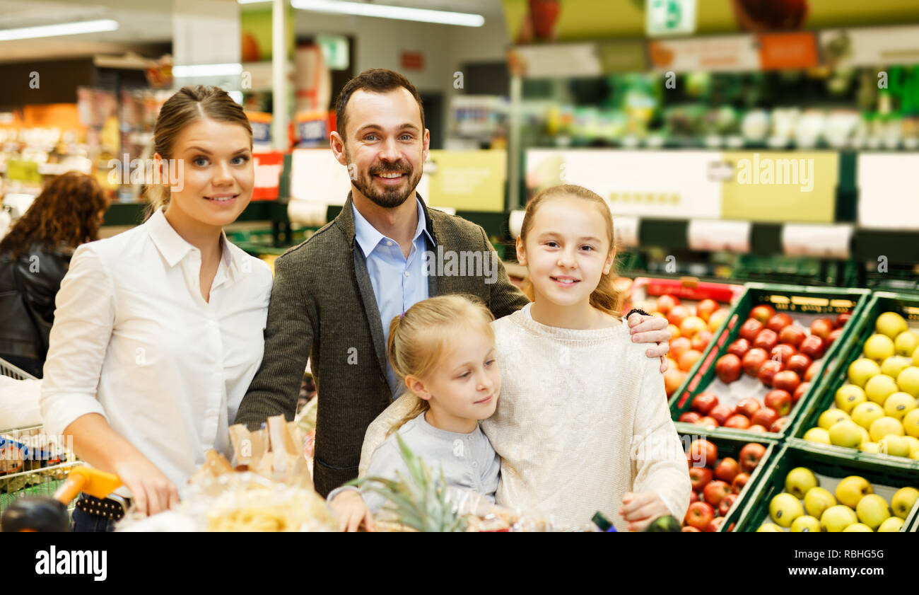 Happy family is standing with trolley with food for dinner in the ...