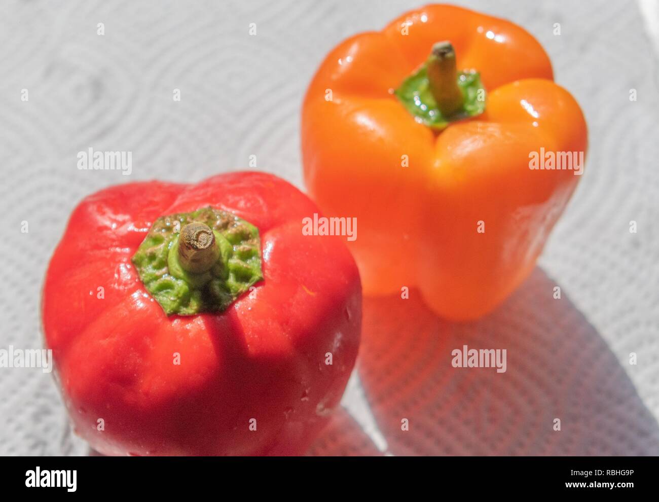 An orange and red colored capsicum against a white textured background ...
