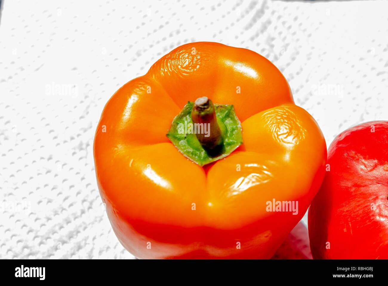 An orange colored capsicum against a white textured background Stock ...