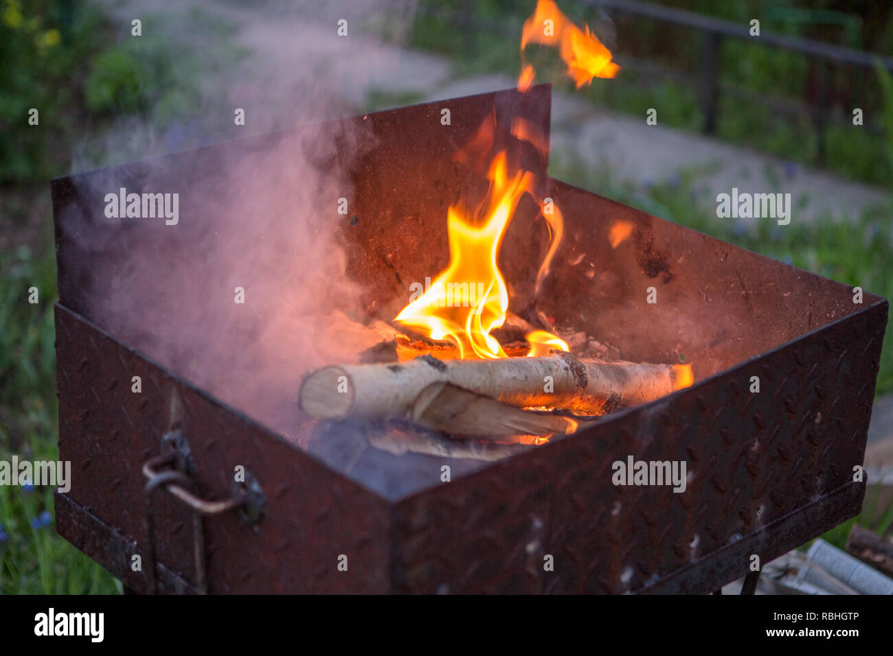 Barbecue with burning log, smoke Stock Photo - Alamy