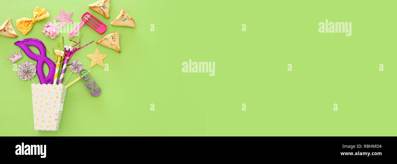 Purim celebration concept (jewish carnival holiday) over green wooden ...