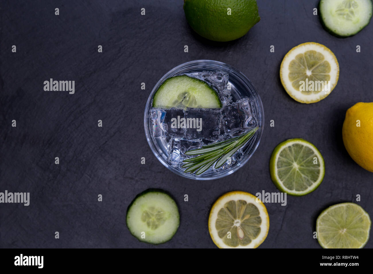 Gin tonic cocktail drink glass with ice cucumber lime lemon dark ...