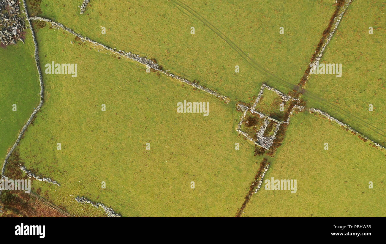 Overhead aerial view of green fields with old stone house ruin in North ...