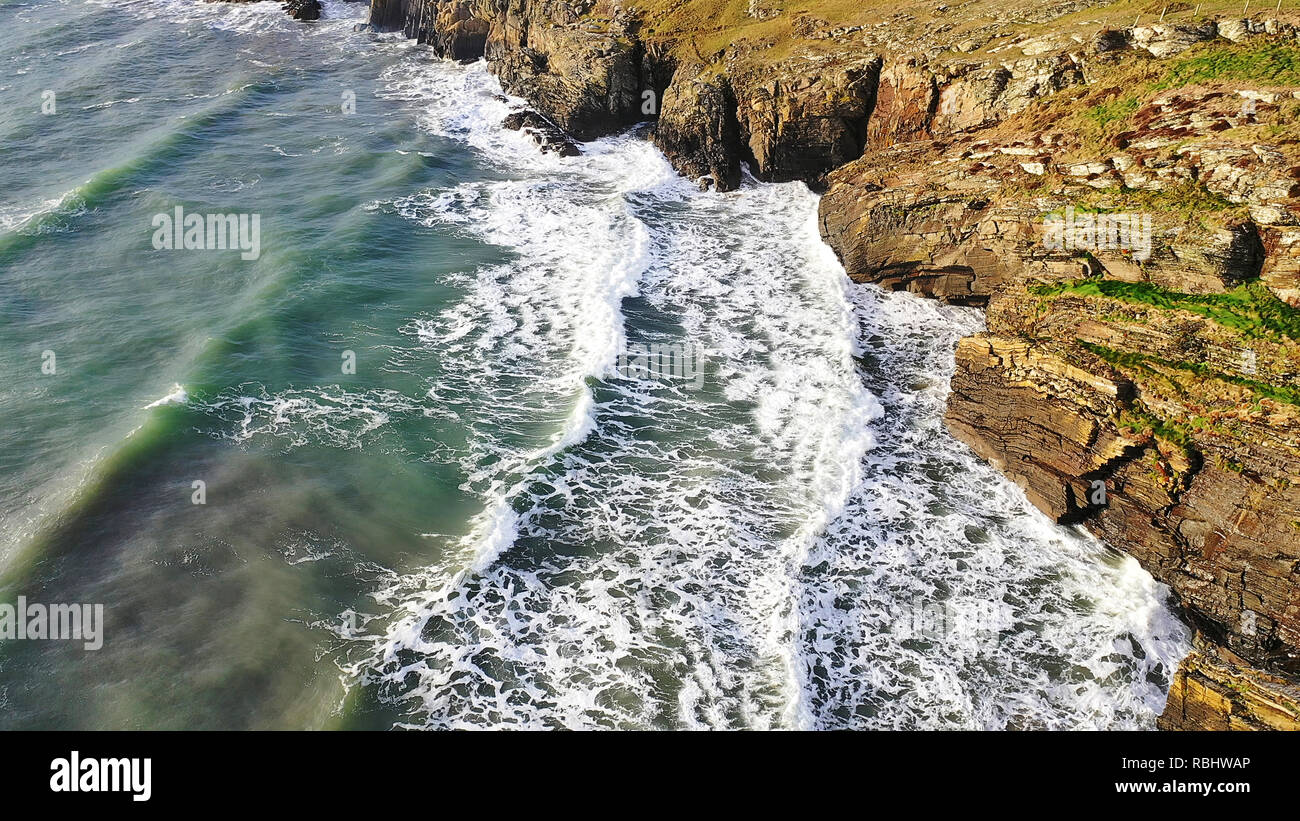 Aerial overhead view of beautiful breaking ocean waves against a rugged ...