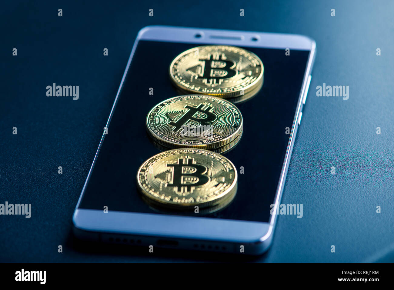 Physical bitcoin coin on the phone screen. The concept of ...