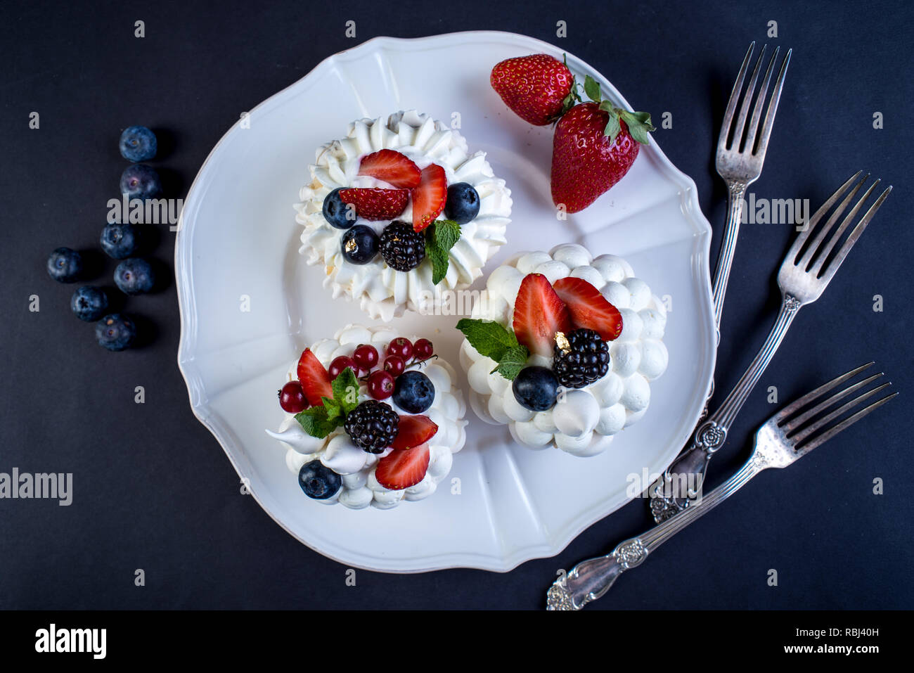 Delicate white meringues with fresh berries on the plate. Dessert ...