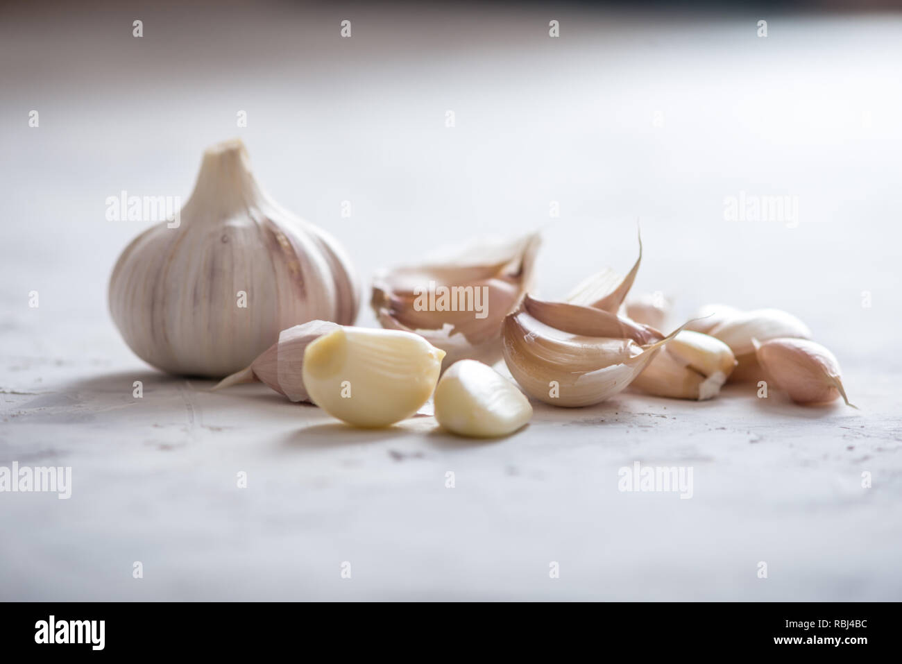 Group of garlic cloves scattered on a table on a white background. An ...