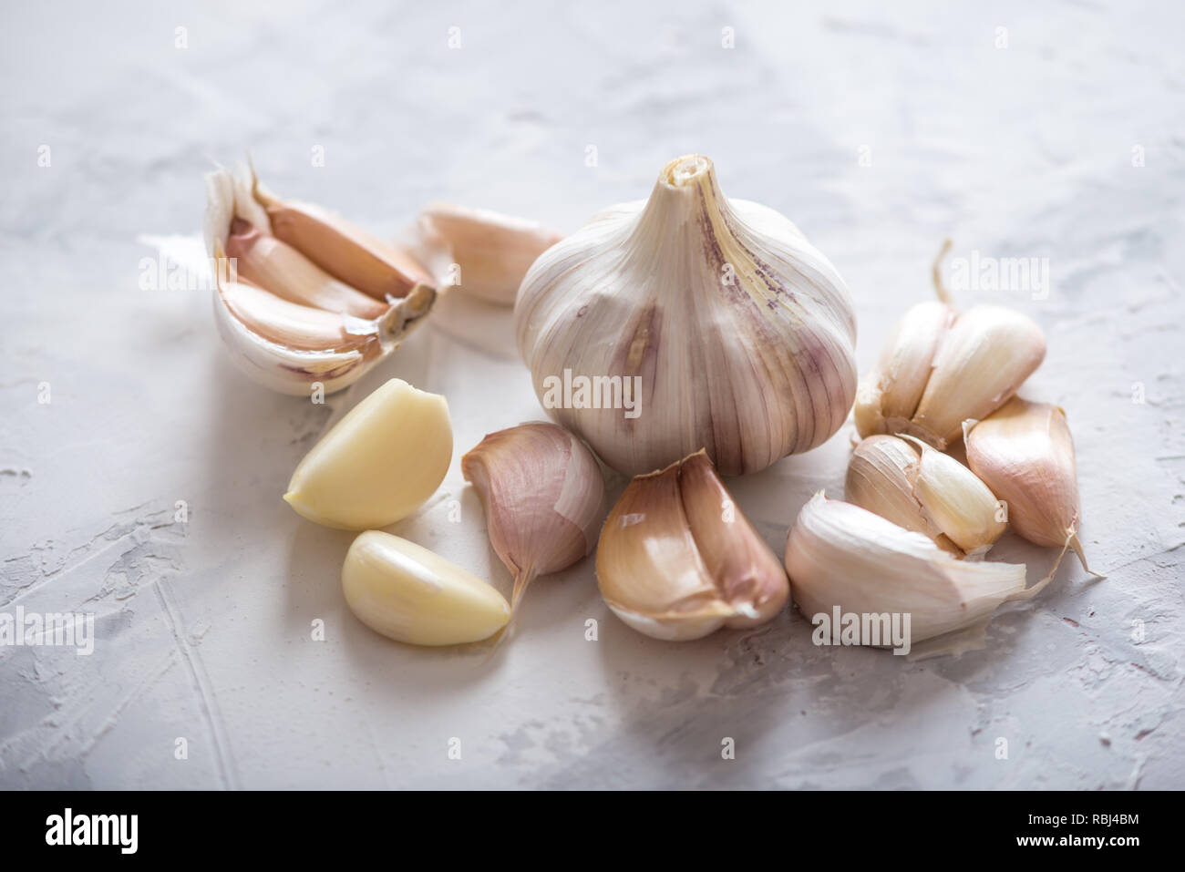 Group of garlic cloves scattered on a table on a white background. An ...