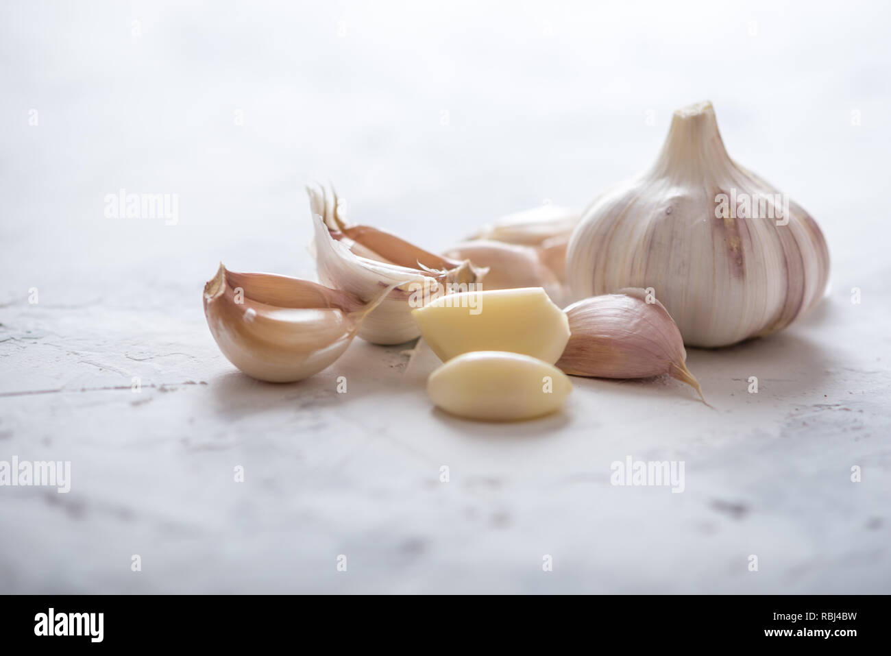 Group of garlic cloves scattered on a table on a white background. An ...