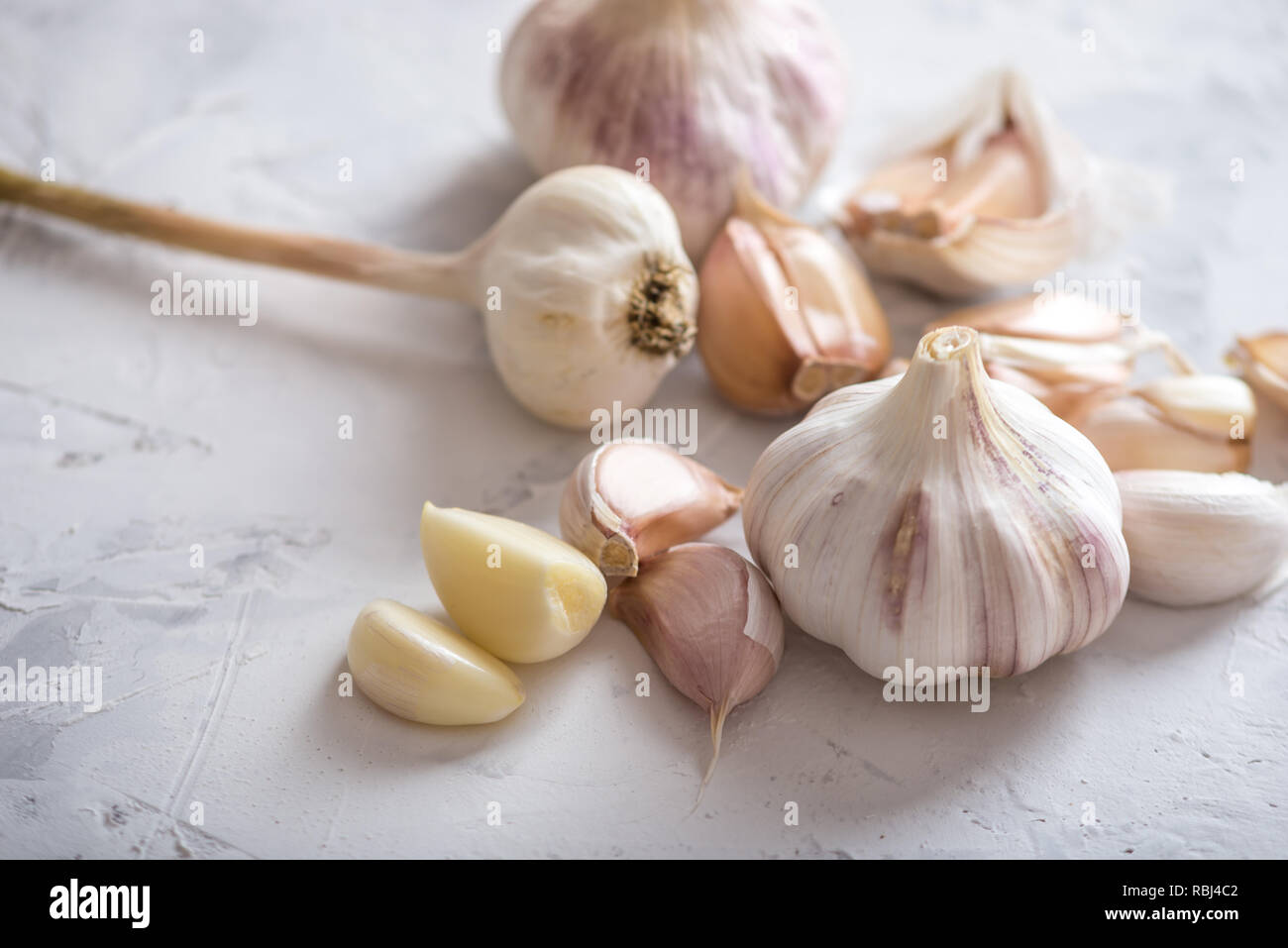 Group of garlic cloves scattered on a table on a white background. An ...