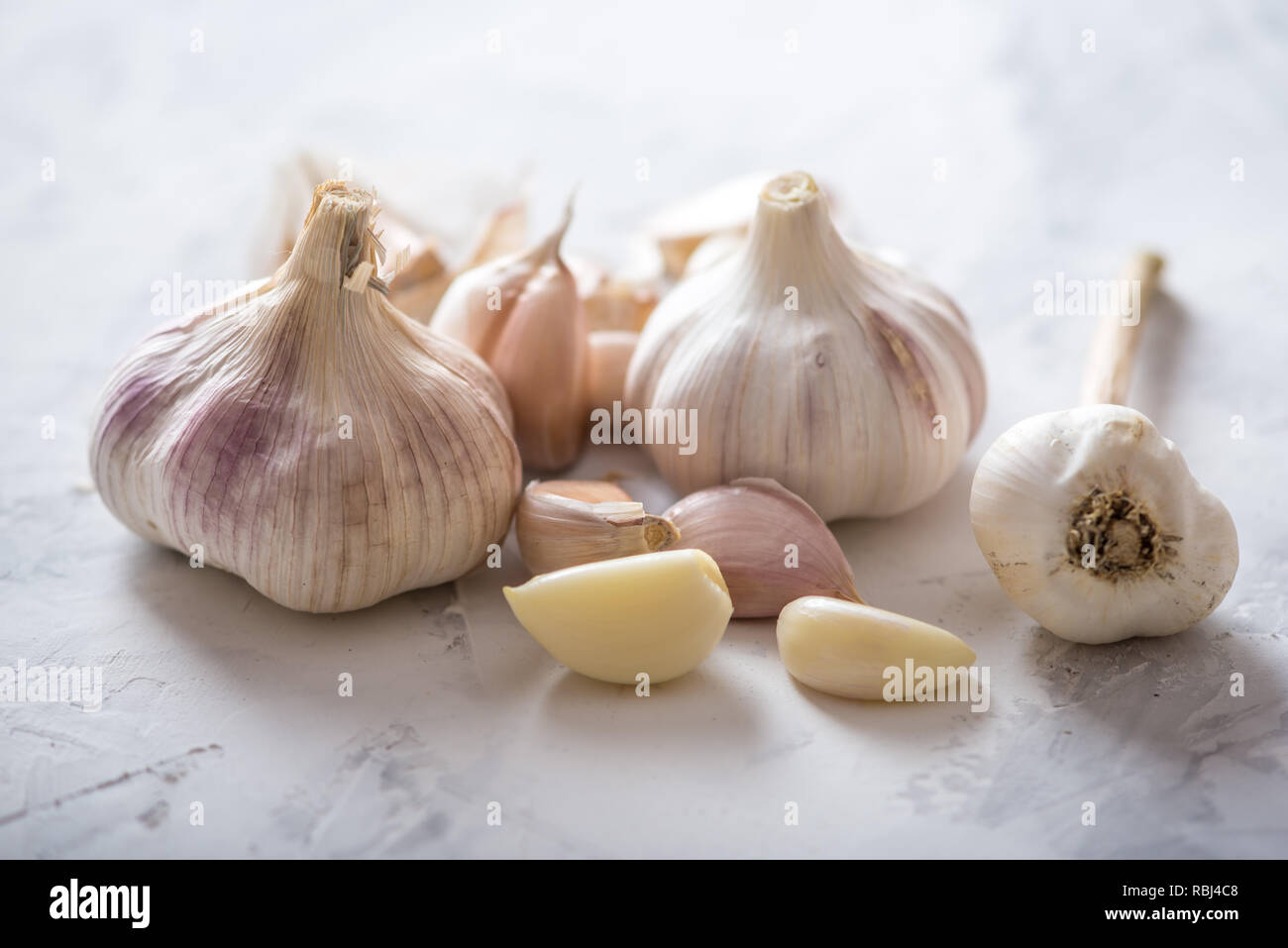 Group of garlic cloves scattered on a table on a white background. An ...