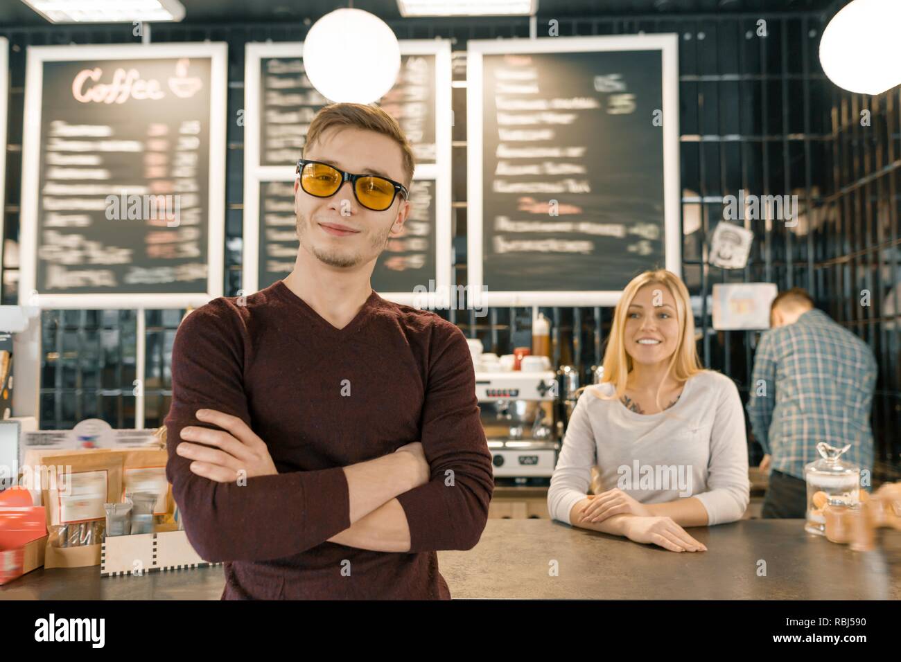 Young team of three cafe workers, people posing and smiling at coffee ...