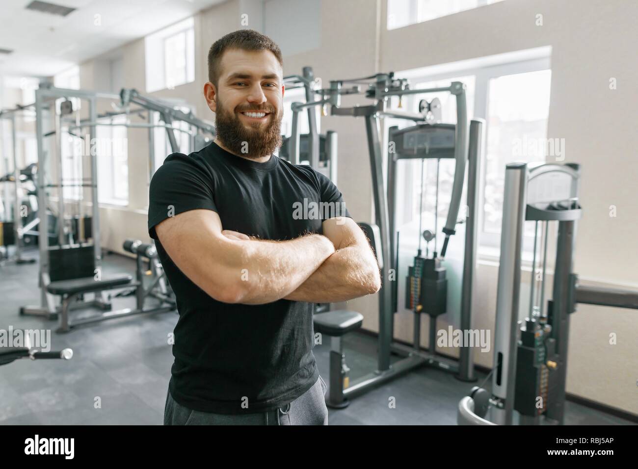 Smiling positive confident male personal instructor with arms crossed ...