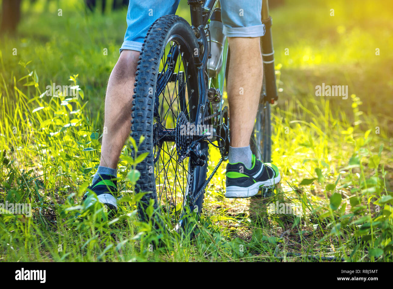 Cyclist on a green mountain bike in the woods riding on the grass ...