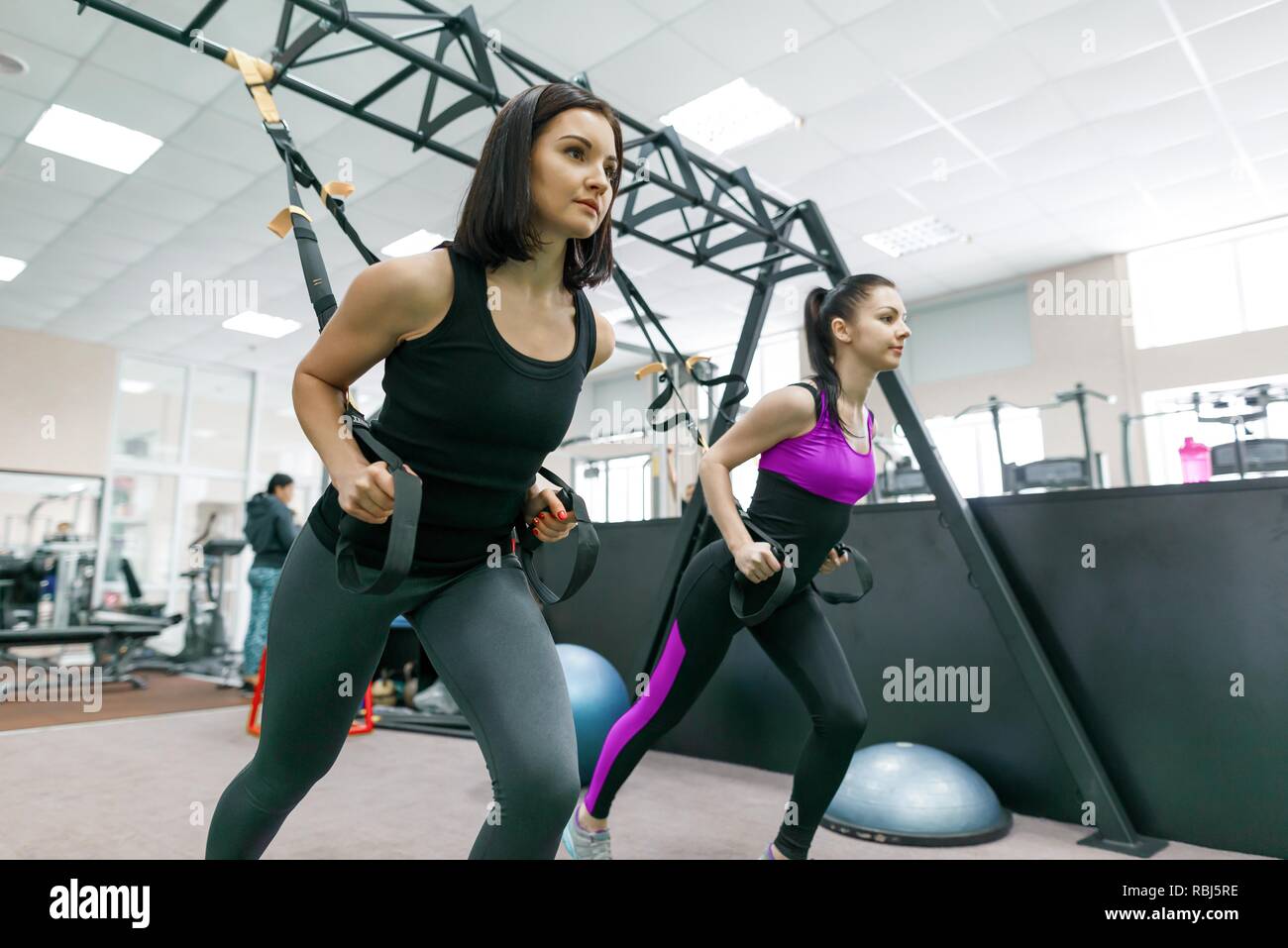 Group training with fitness loops in the gym, two young attractive ...