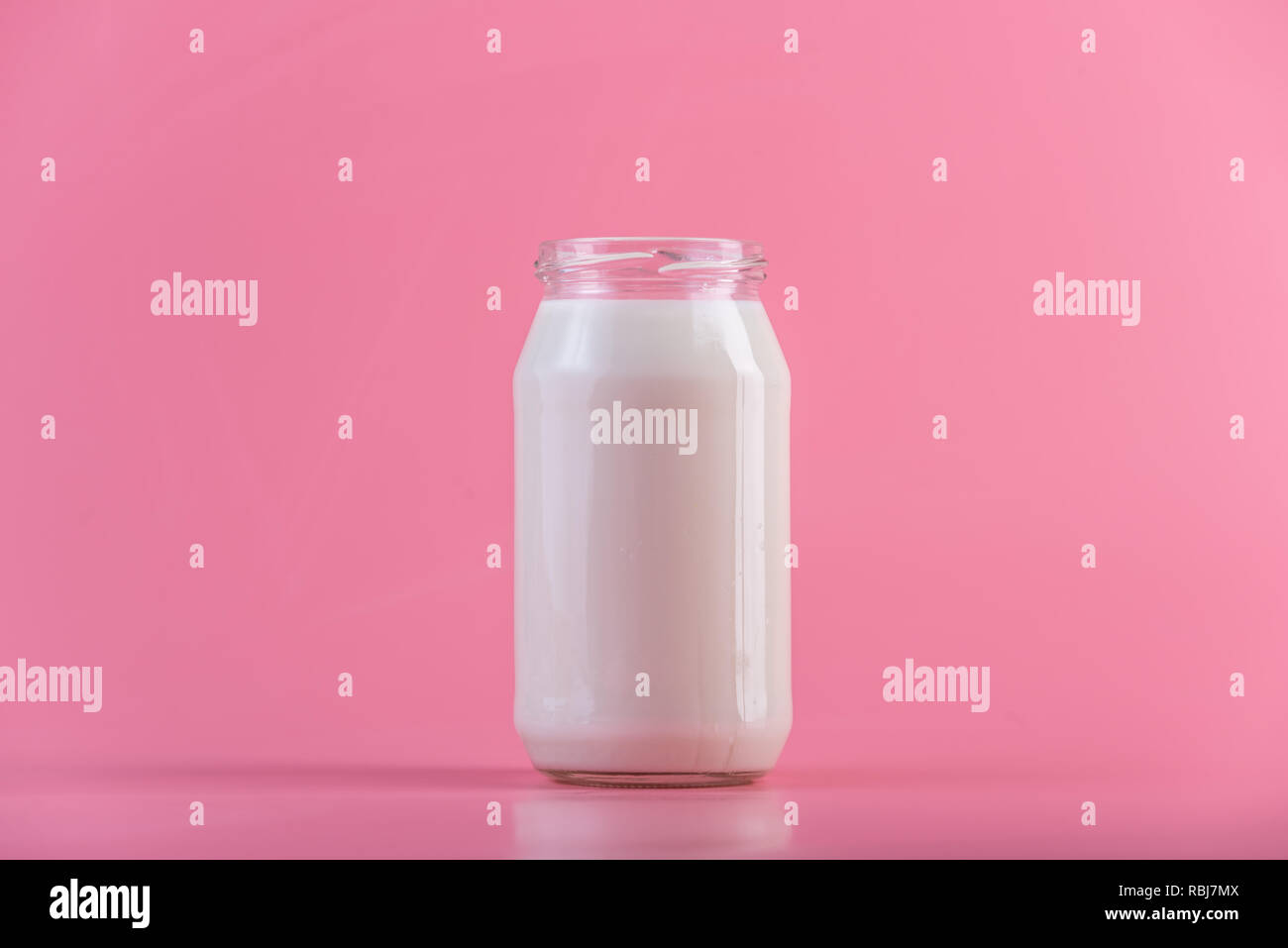 Glass bottle with fresh milk on pink background. Colorful minimalism ...