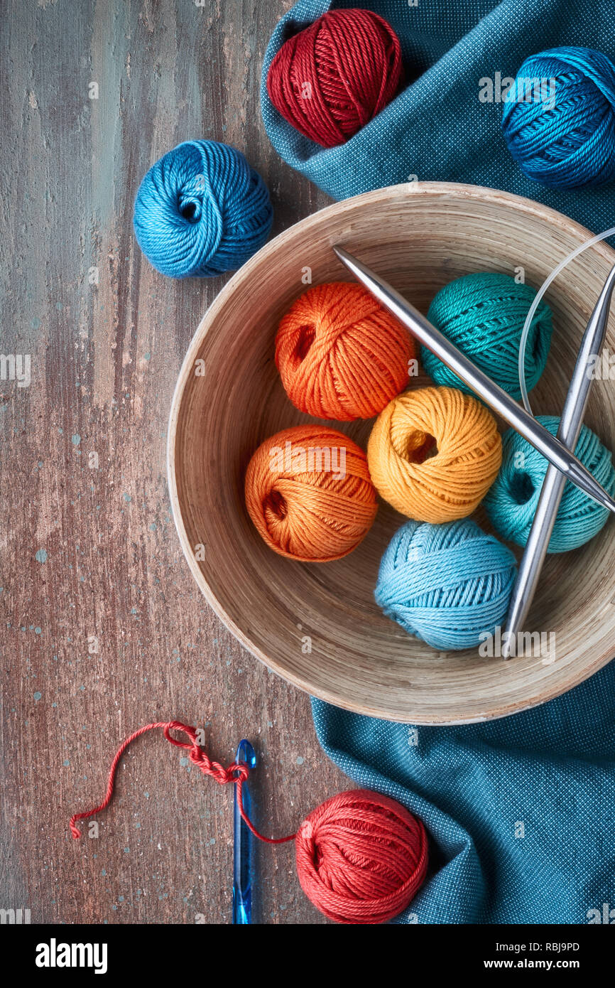 Top view of various yarn balls and latch hook on textured background ...