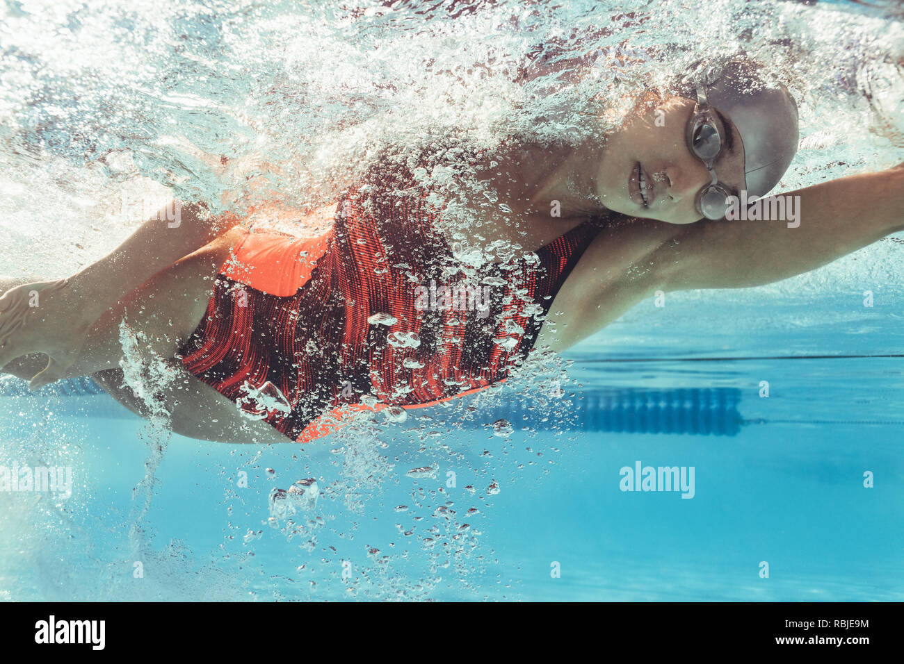 Underwater shot of young female swimmer in action. Young female swimmer ...