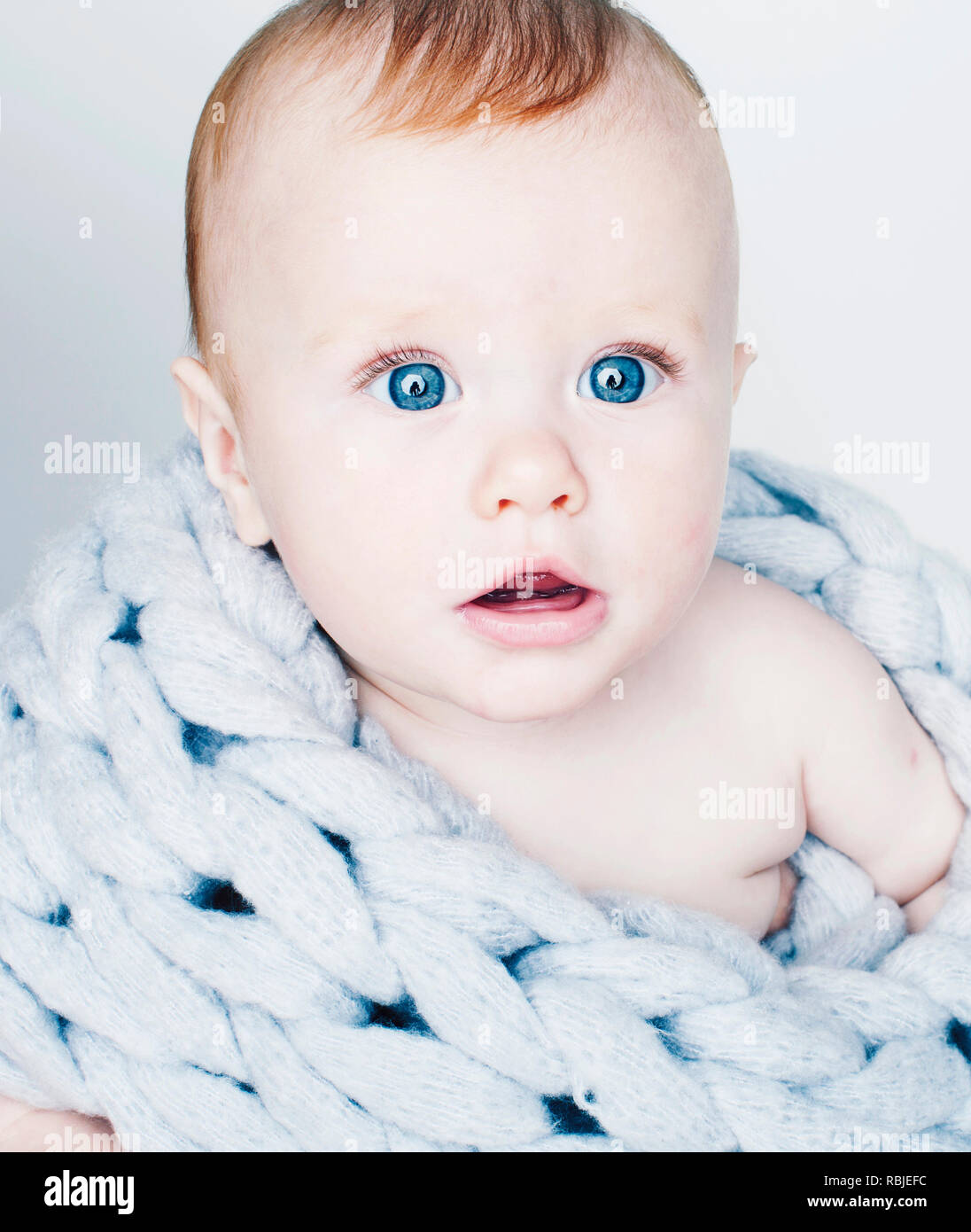 little cute red head baby in scarf all over him close up isolate Stock ...