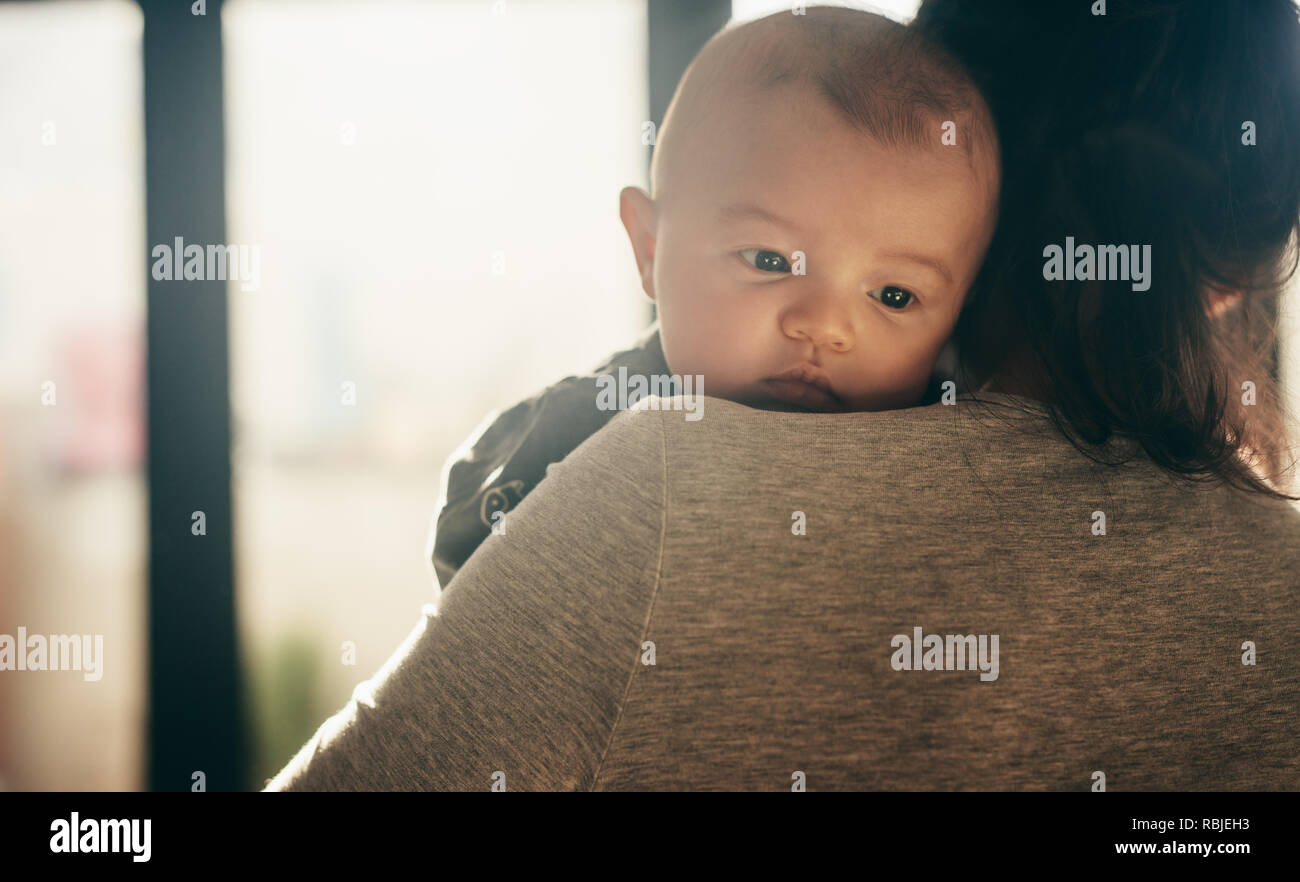 Rear view of a mother carrying her baby. Baby staying calm with his ...