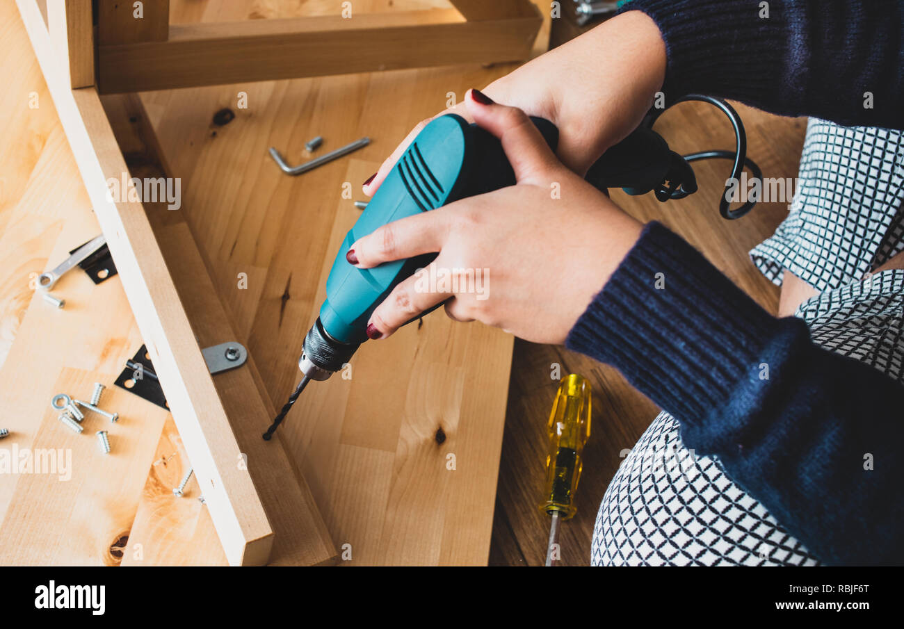 Woman assembly wooden furniture,fixing or repairing house with drill ...
