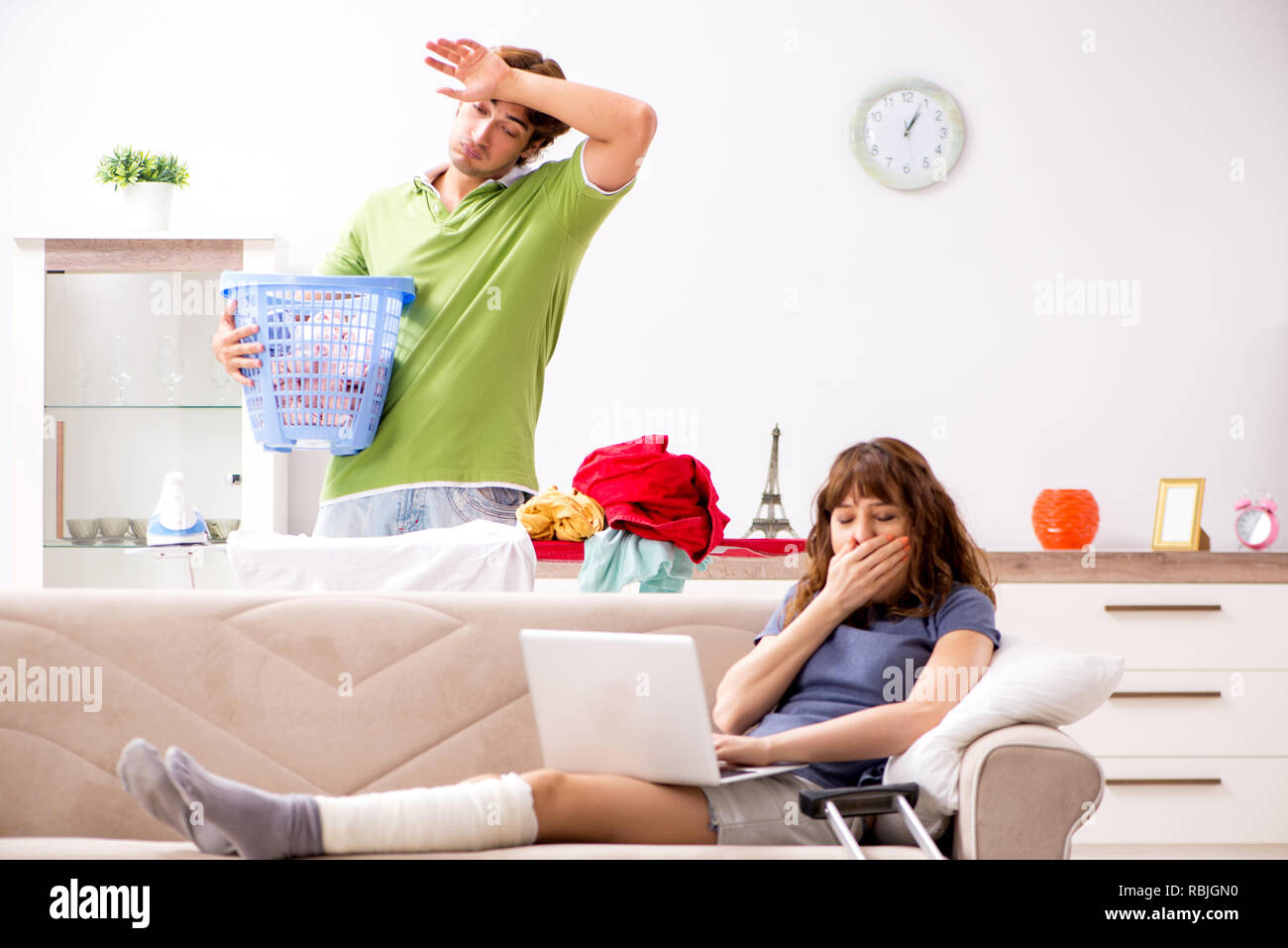 Husband helping leg injured wife in housework Stock Photo - Alamy