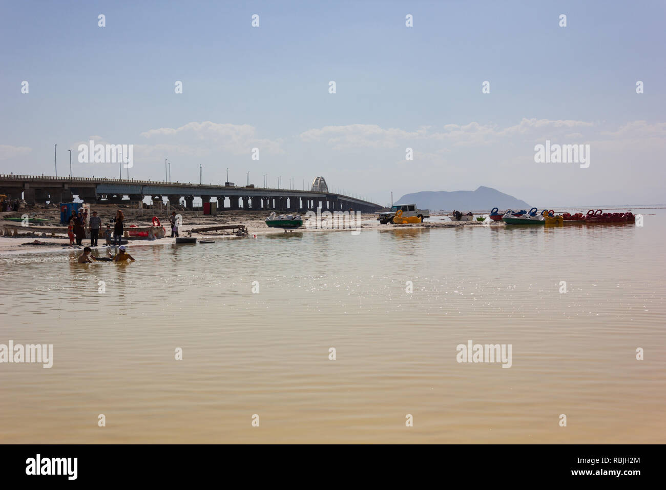 People walking and swimming in shallow waters of salt lake Urmia, West ...