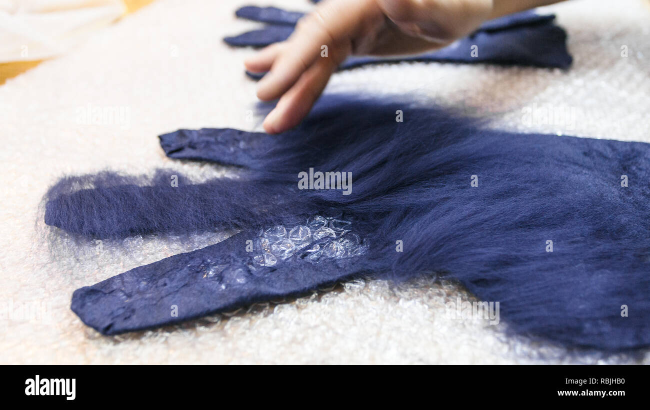 workshop of hand making a fleece gloves from blue Merino sheep wool ...