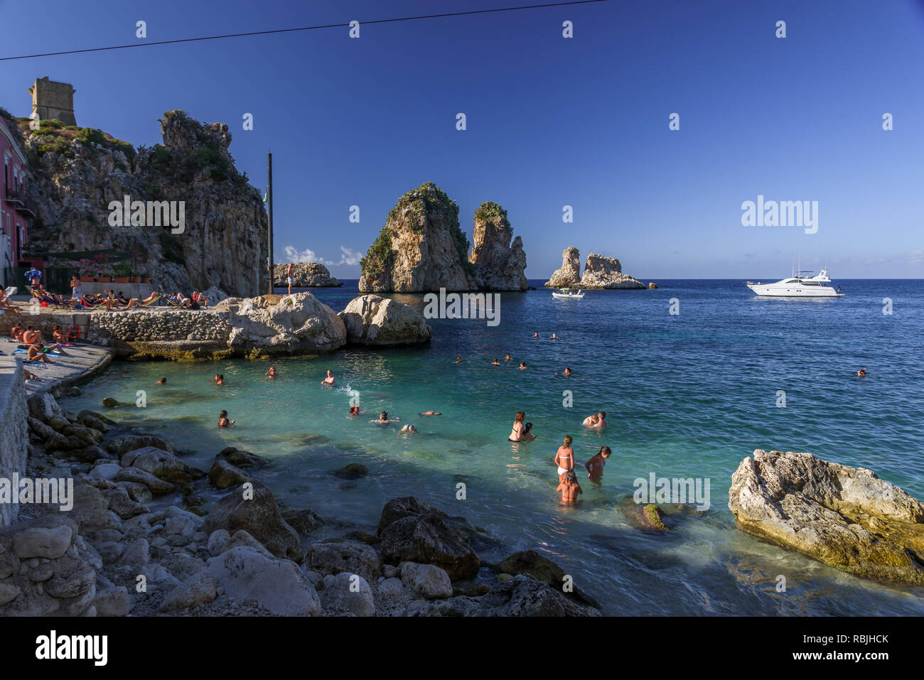 People sunbathing and swimming in the crystal clear sea water at the ...