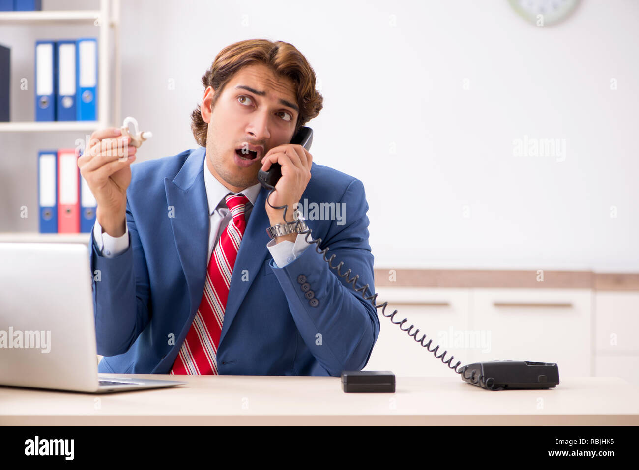 Deaf employee using hearing aid in office Stock Photo - Alamy