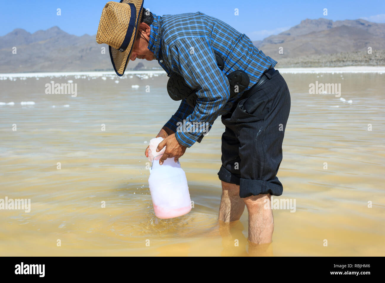 The man in shallow waters of salt lake Urmia is picking up some salt ...