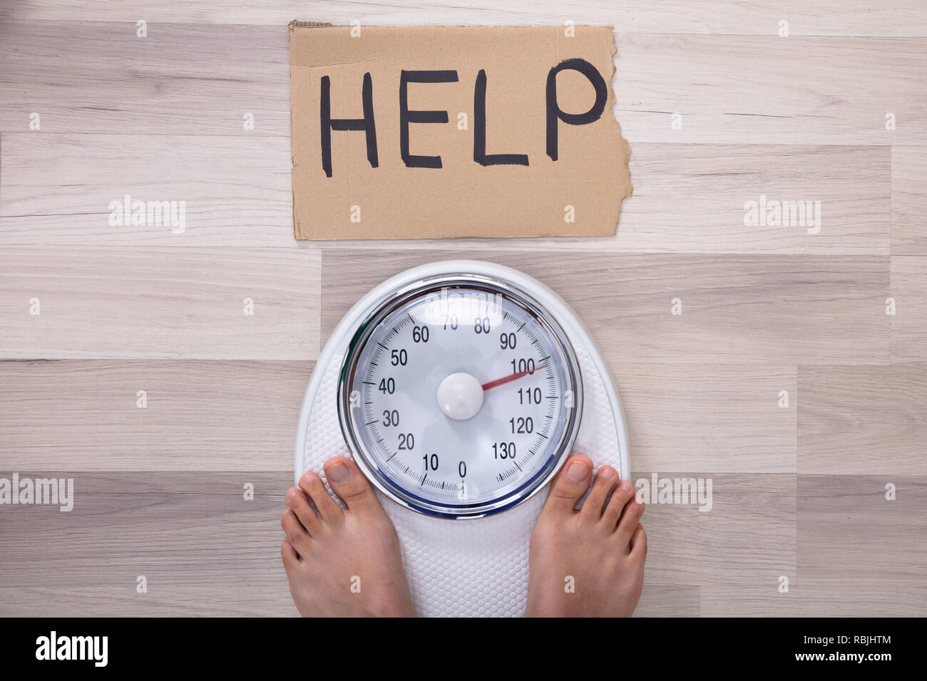 Elevated View Of Help Sign On Cardboard With Woman's Feet On Weighing ...