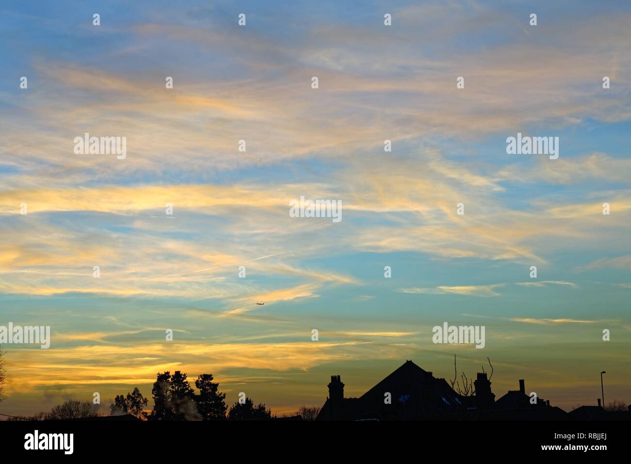 Hazy winter sunset and clouds over rooftops in Surrey England UK Stock ...
