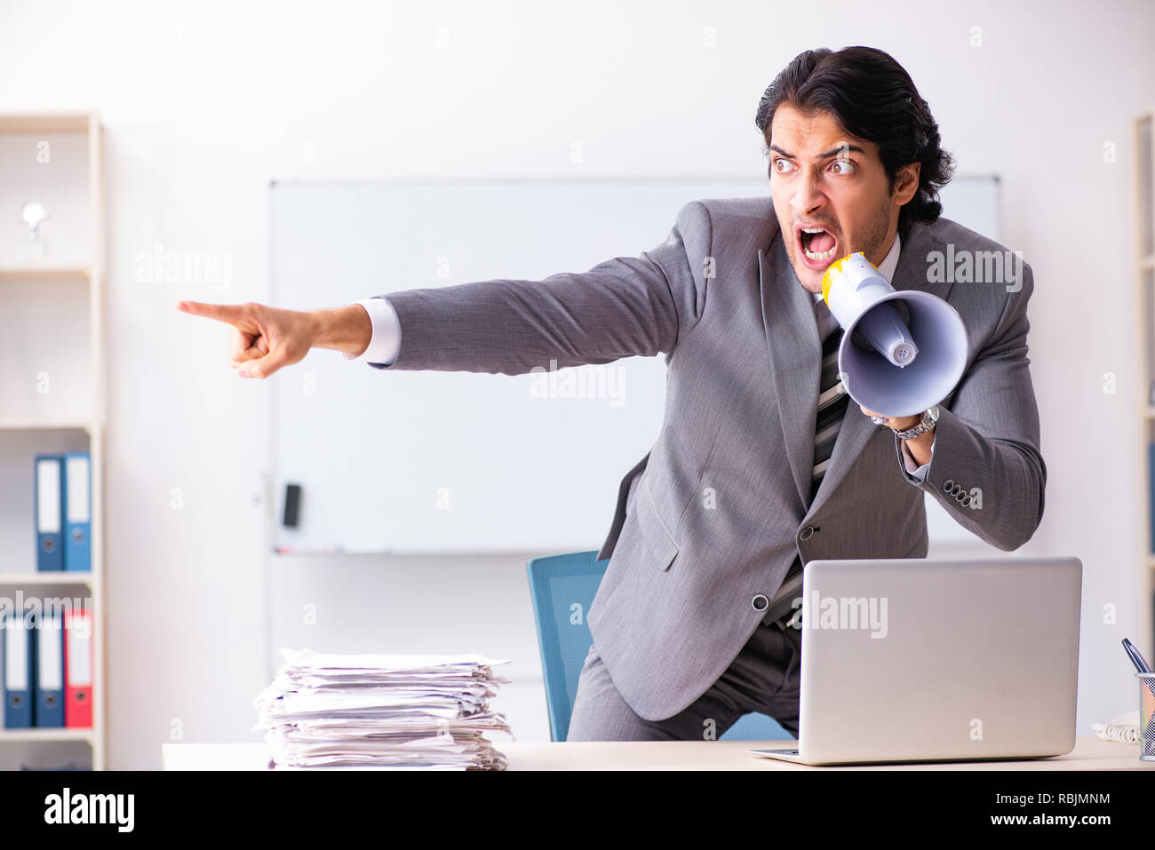 Young employee boss with megaphone in the office Stock Photo - Alamy