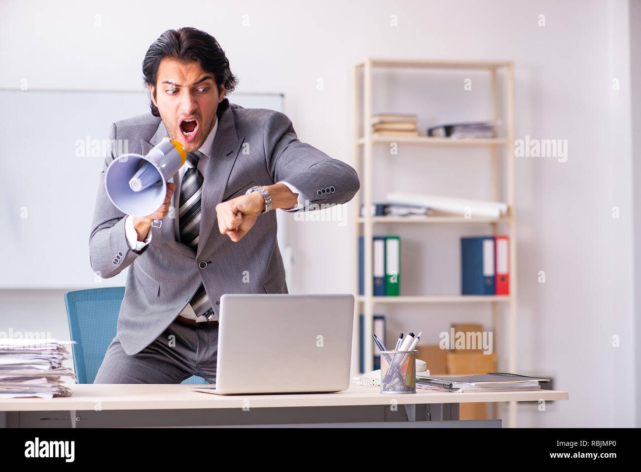 Young employee boss with megaphone in the office Stock Photo - Alamy