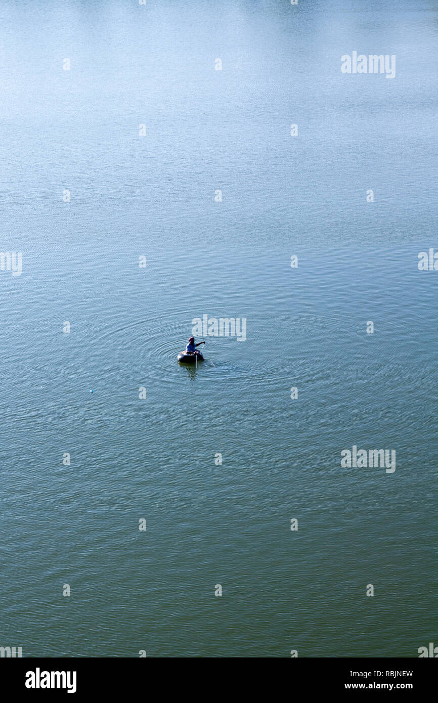 Fisherman fishing alone in a lake Stock Photo - Alamy
