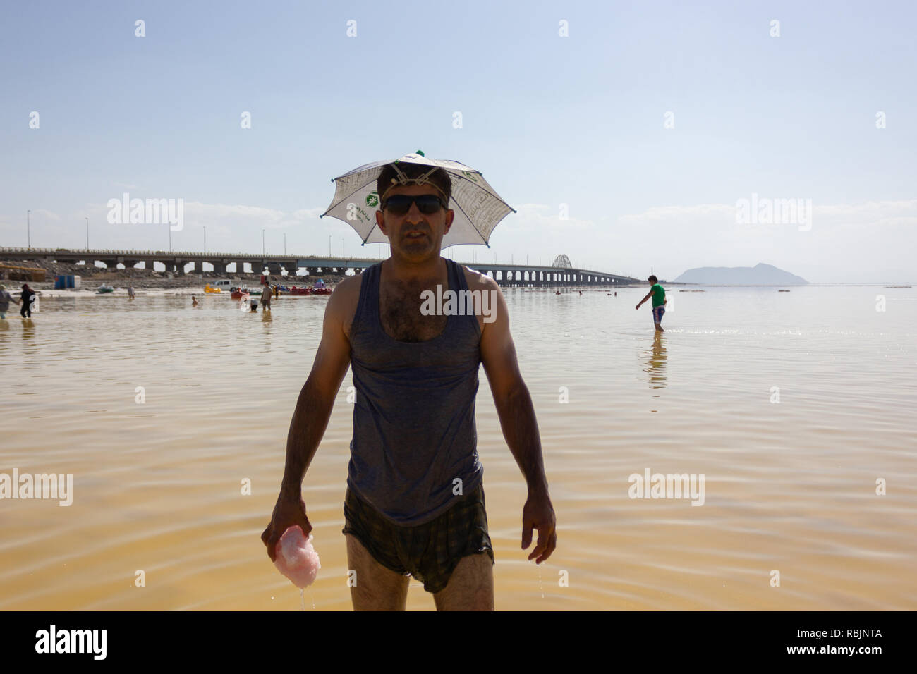 A man standing in the salt Urmia Lake with a stone salt on his hand ...